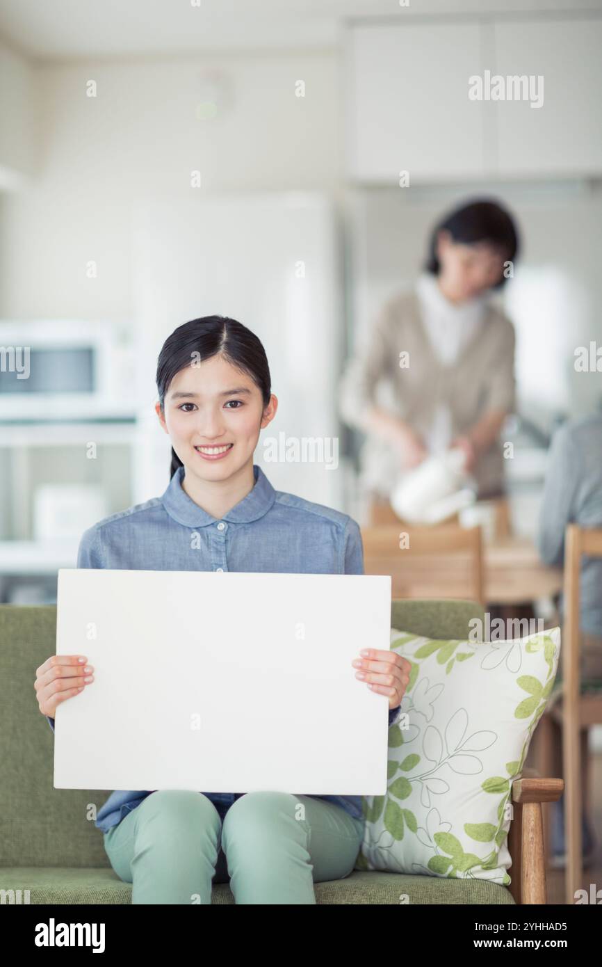 Girl sitting on sofa holding whiteboard Stock Photo - Alamy