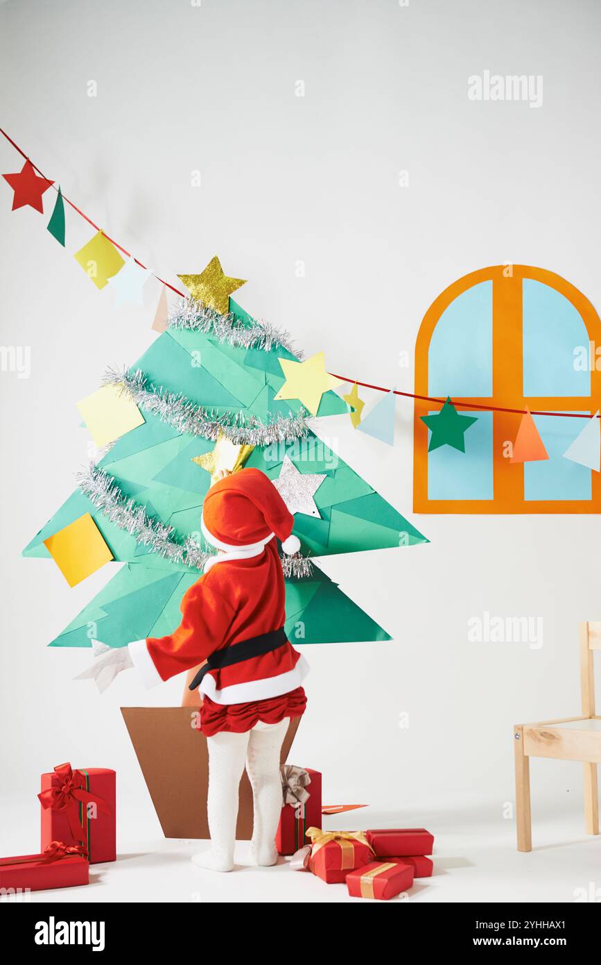 Girl dressed as Father Christmas decorating Christmas tree Stock Photo ...
