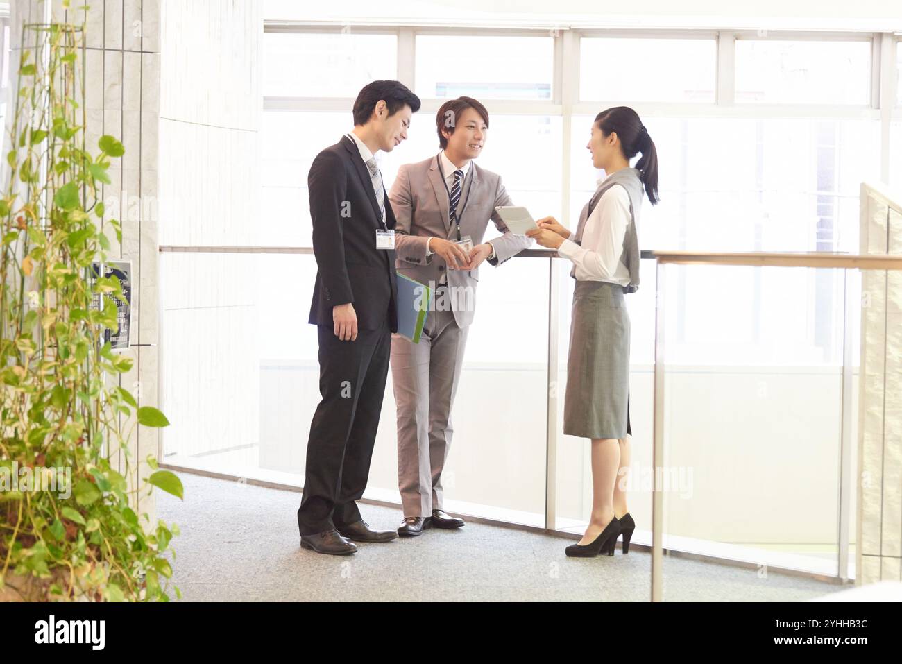 Businessman and colleague talking in corridor Stock Photo - Alamy