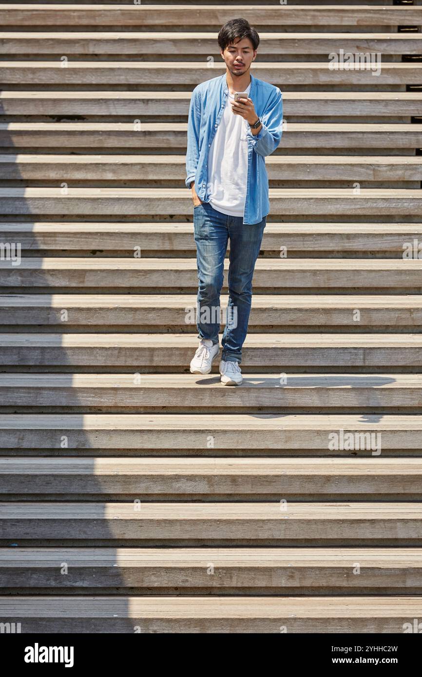 Man descending stairs while looking at his smartphone Stock Photo - Alamy