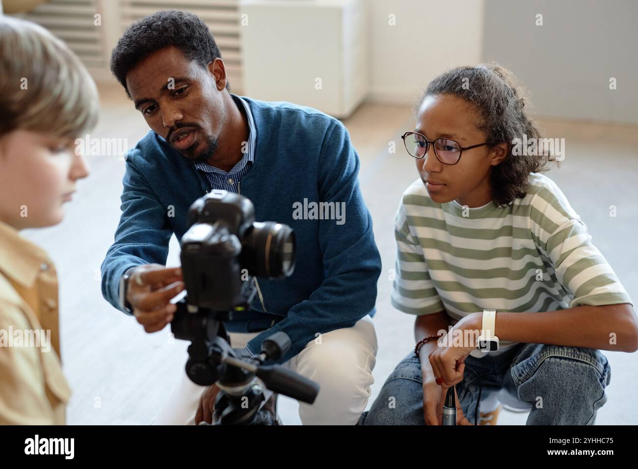 Portrait of African American man as male teacher helping children ...