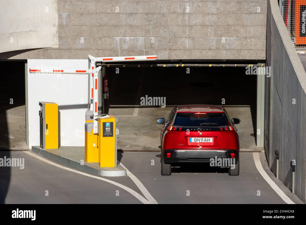 Red car entering underground parking garage passing through open ...