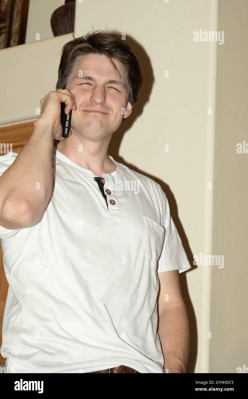 Man smiles while talking on the phone indoors during daytime ...