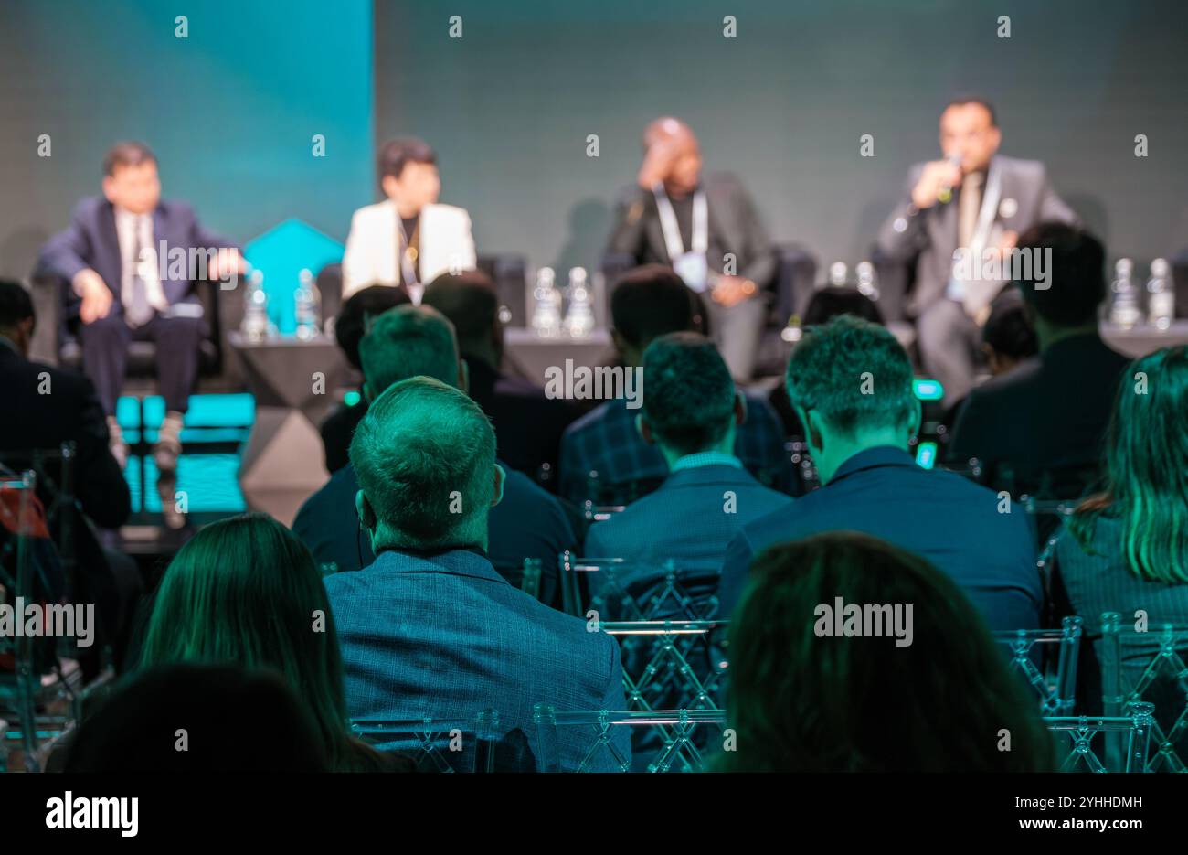 Attendees focus on speakers during business conference panel discussion ...