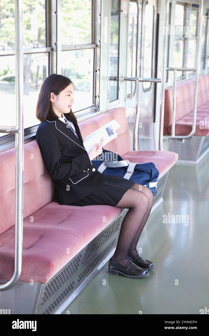 Junior high school girl reading on train Stock Photo - Alamy