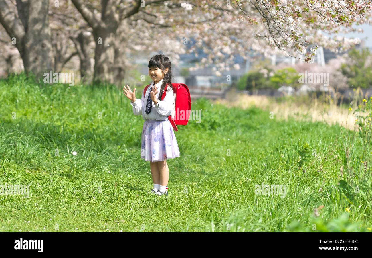 First grade girl waving under the cherry tree Stock Photo - Alamy