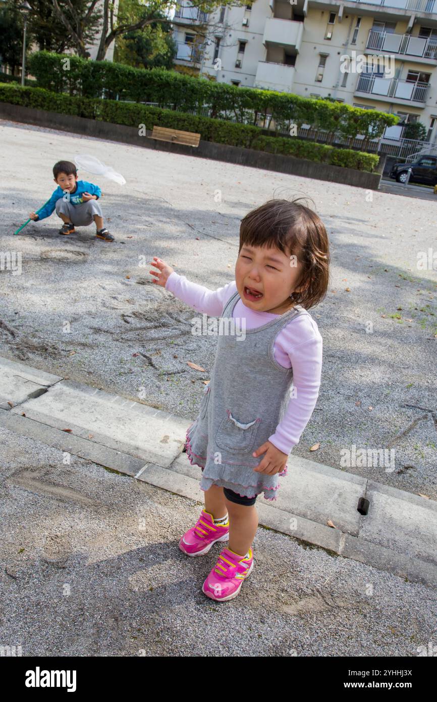 Crying girl and boy sitting and playing with sand Stock Photo - Alamy