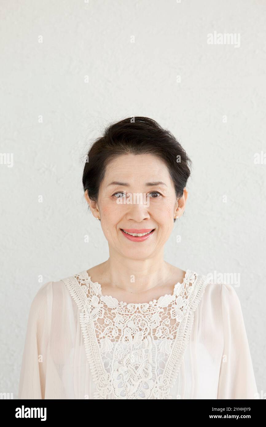 Woman in her 60s smiling with white backpack Stock Photo - Alamy