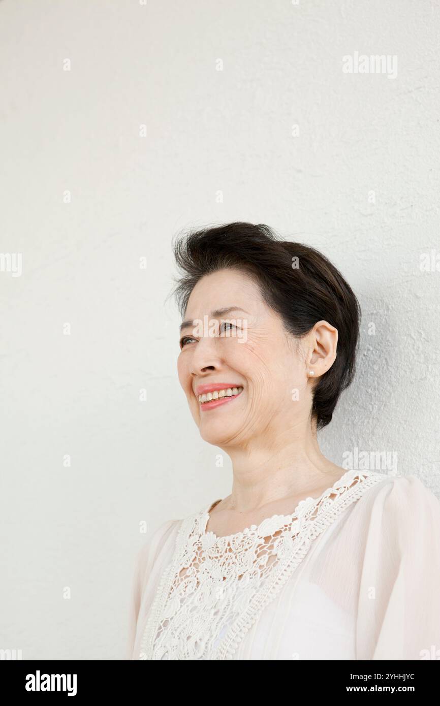Woman in her 60s smiling with white backpack Stock Photo - Alamy