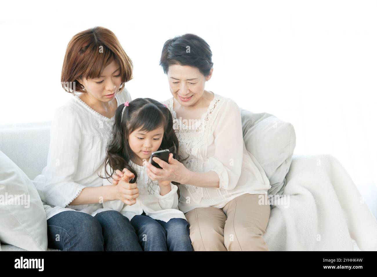 Three generations using smartphones on a sofa Stock Photo - Alamy