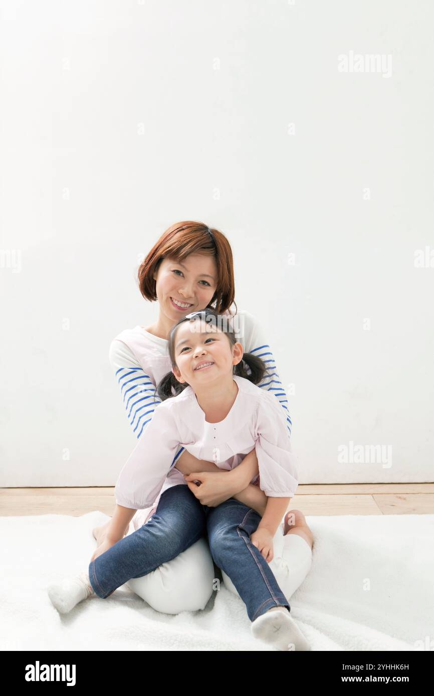 Smiling preschooler sitting on childcare worker's lap Stock Photo - Alamy