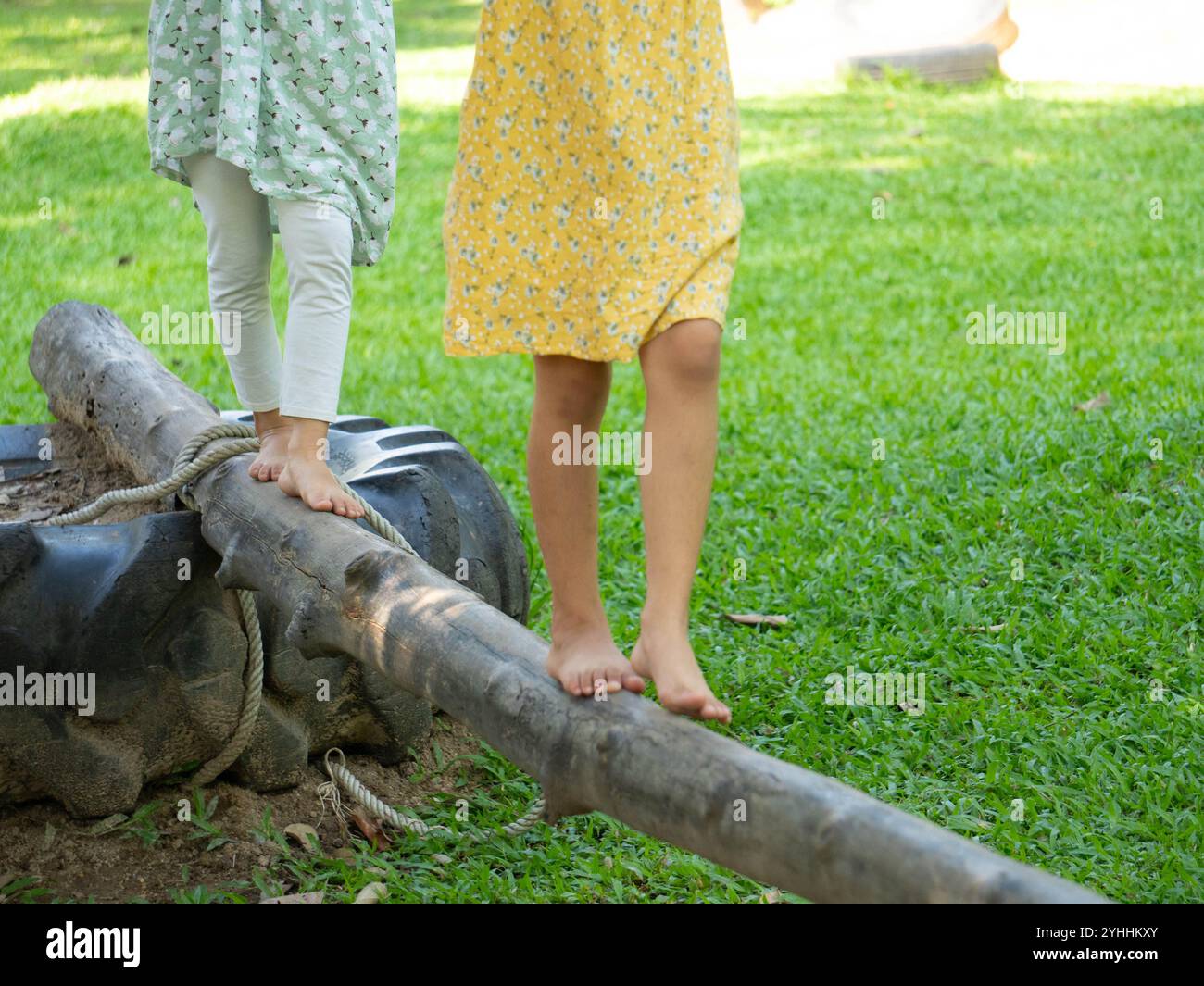 Cute sisters walking on a balance beam in an outdoor park. Children ...