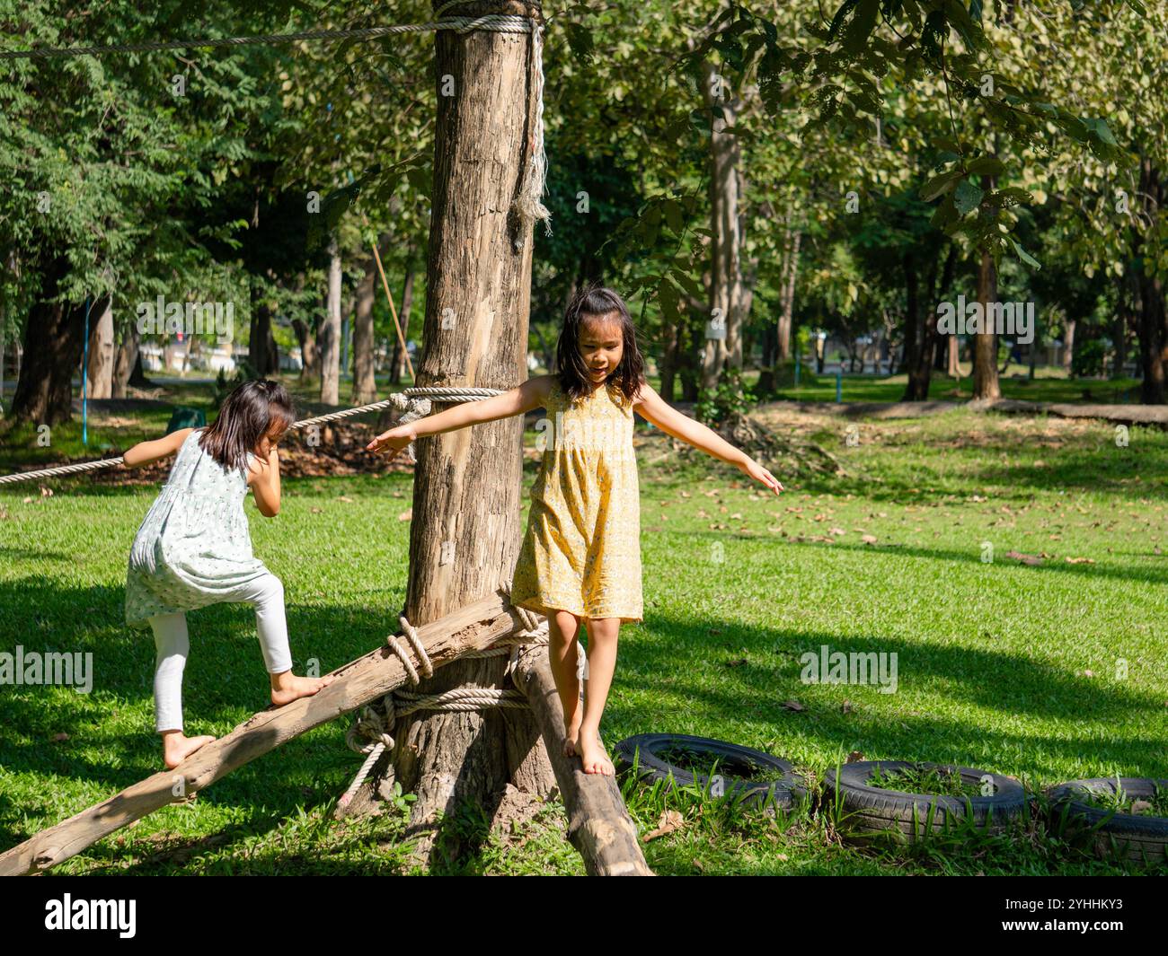 Cute sisters walking on a balance beam in an outdoor park. Children ...