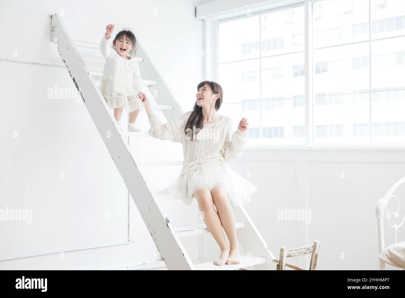 Mother and daughter sitting on ladder playing Stock Photo - Alamy