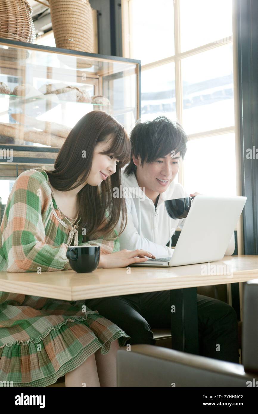 Couple in their 20s sitting side by side on computers Stock Photo - Alamy