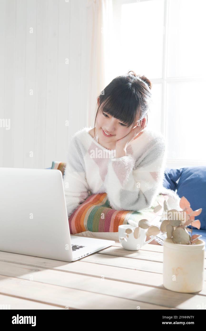 Woman in her 20s staring at laptop computer with elbows on the ground ...