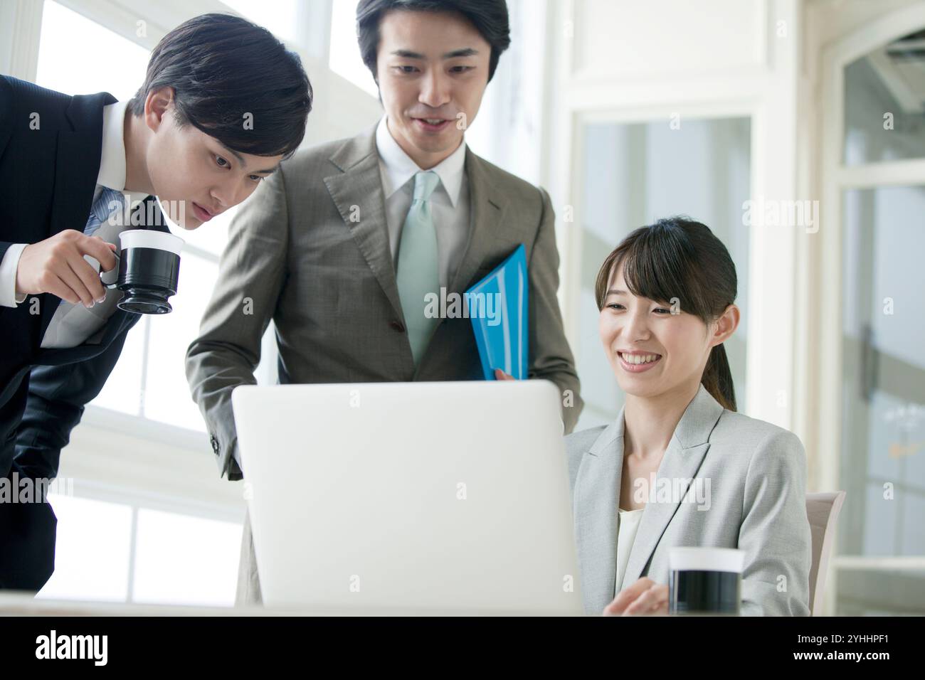 Three office workers looking at a computer screen Stock Photo - Alamy