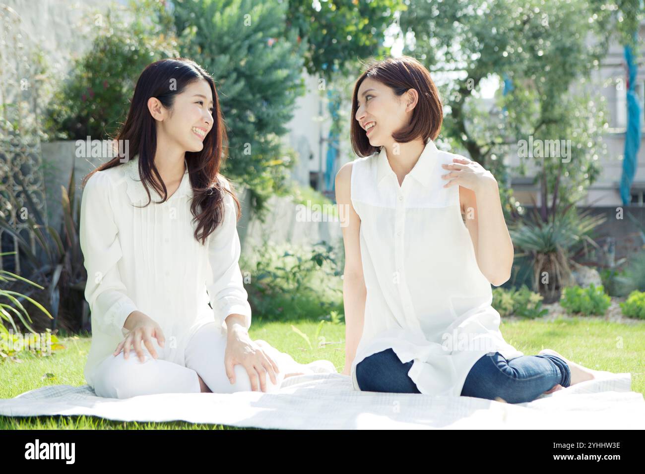 Two women talking in a garden with greenery Stock Photo - Alamy