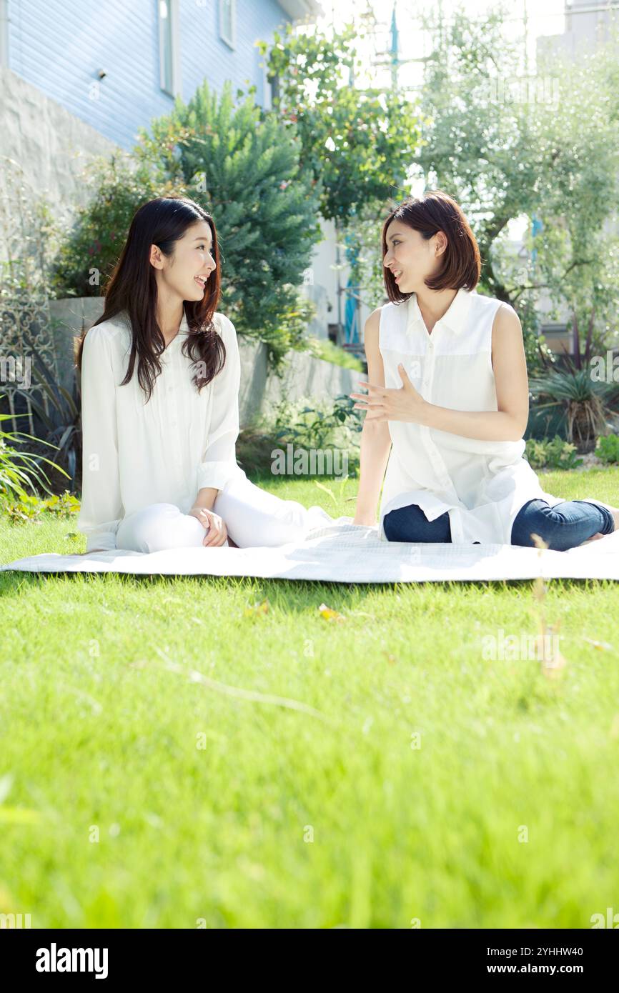 Two women talking in a garden with greenery Stock Photo - Alamy