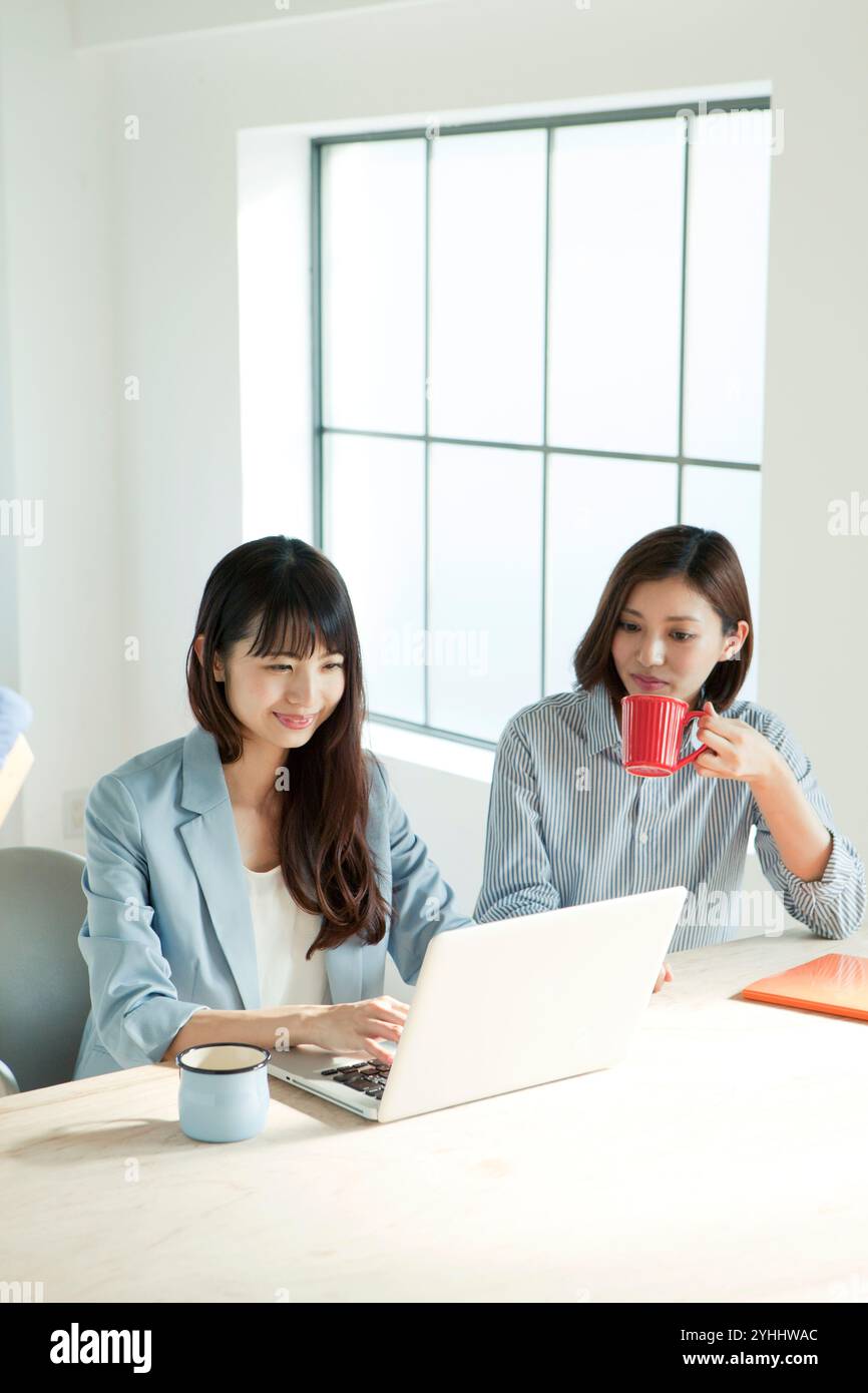 Two women in their 20s using a computer Stock Photo - Alamy
