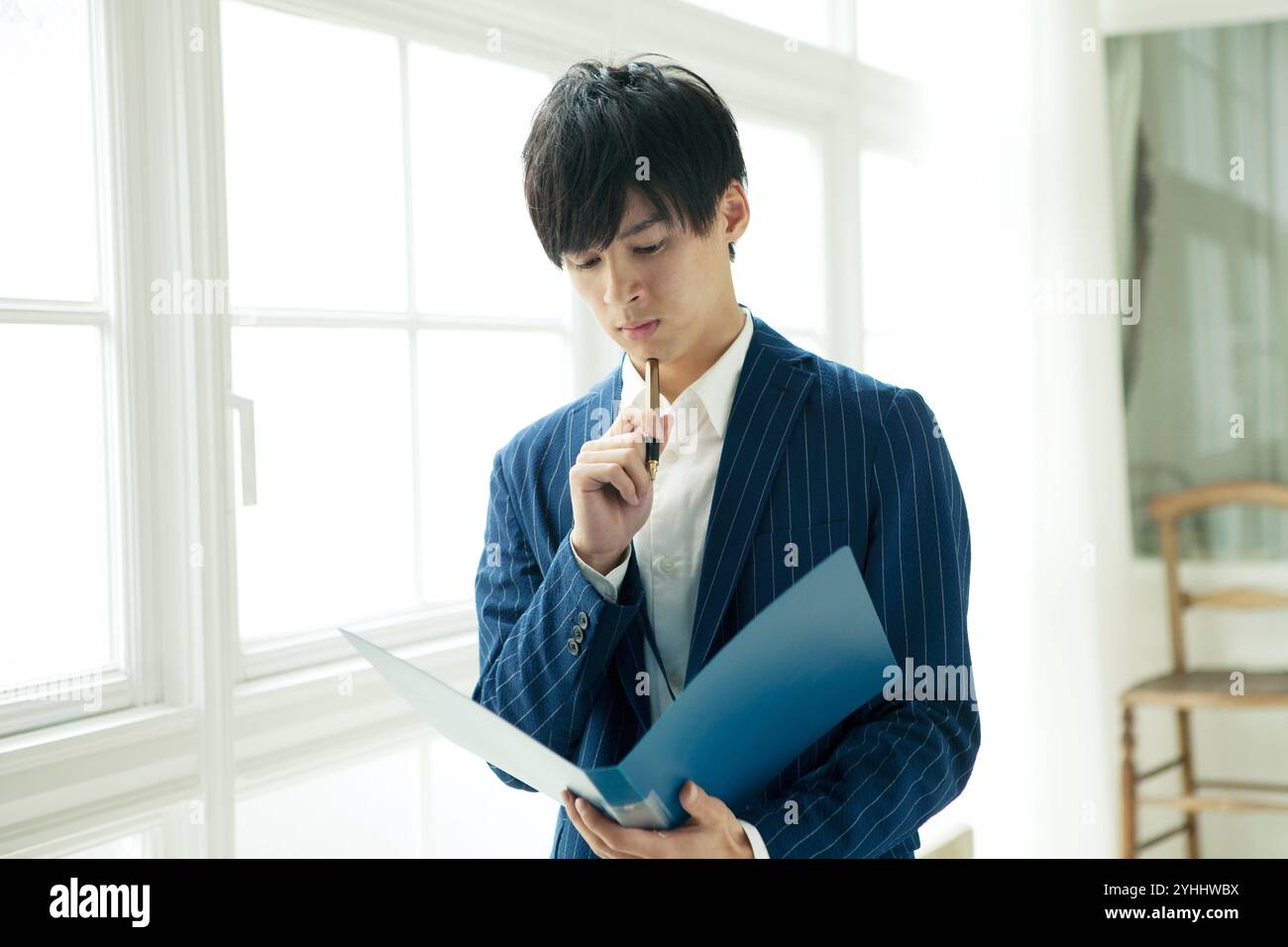 Male in his 20s looking at materials and thinking Stock Photo - Alamy