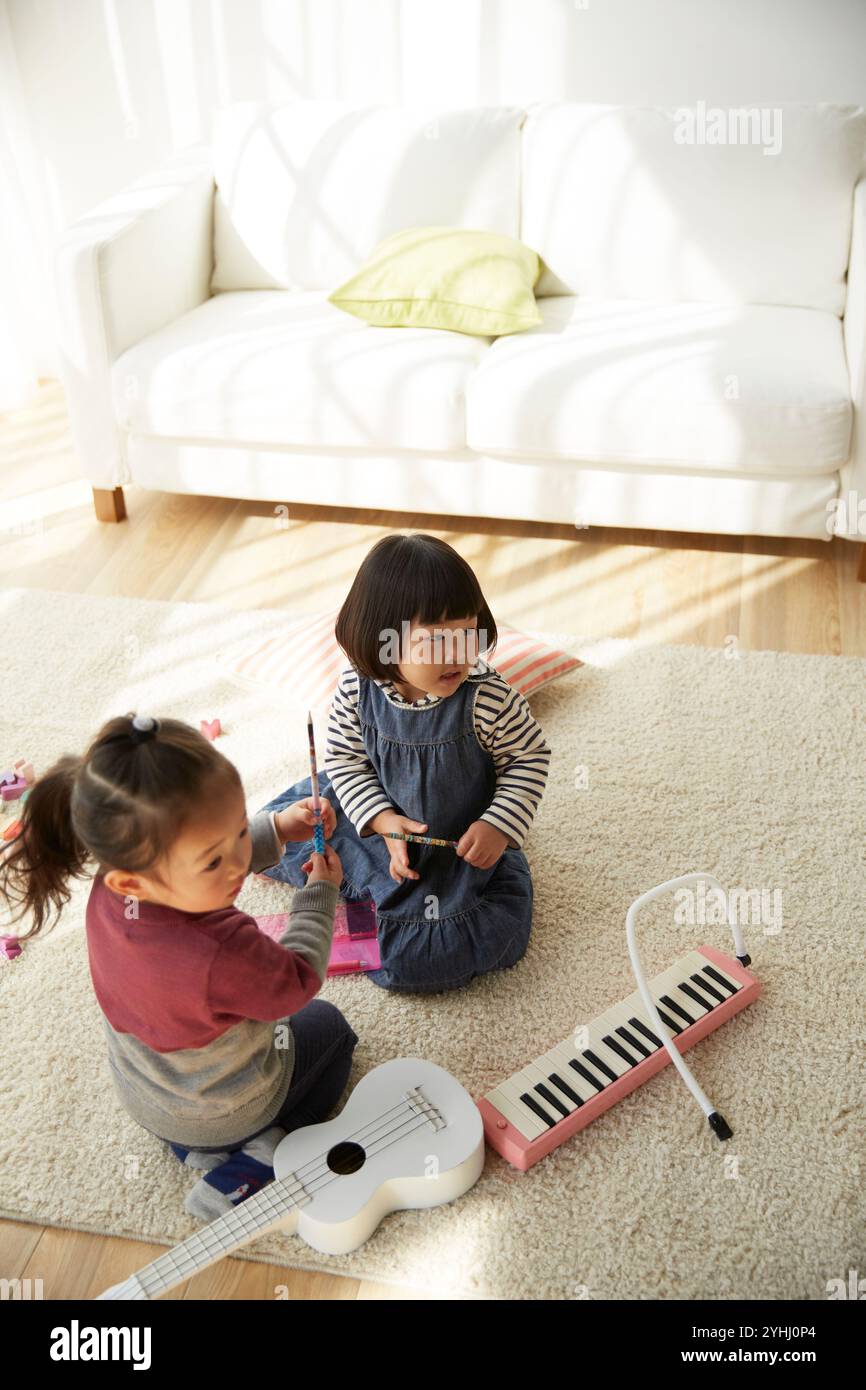 Two girls sitting on carpet with musical instruments Stock Photo - Alamy
