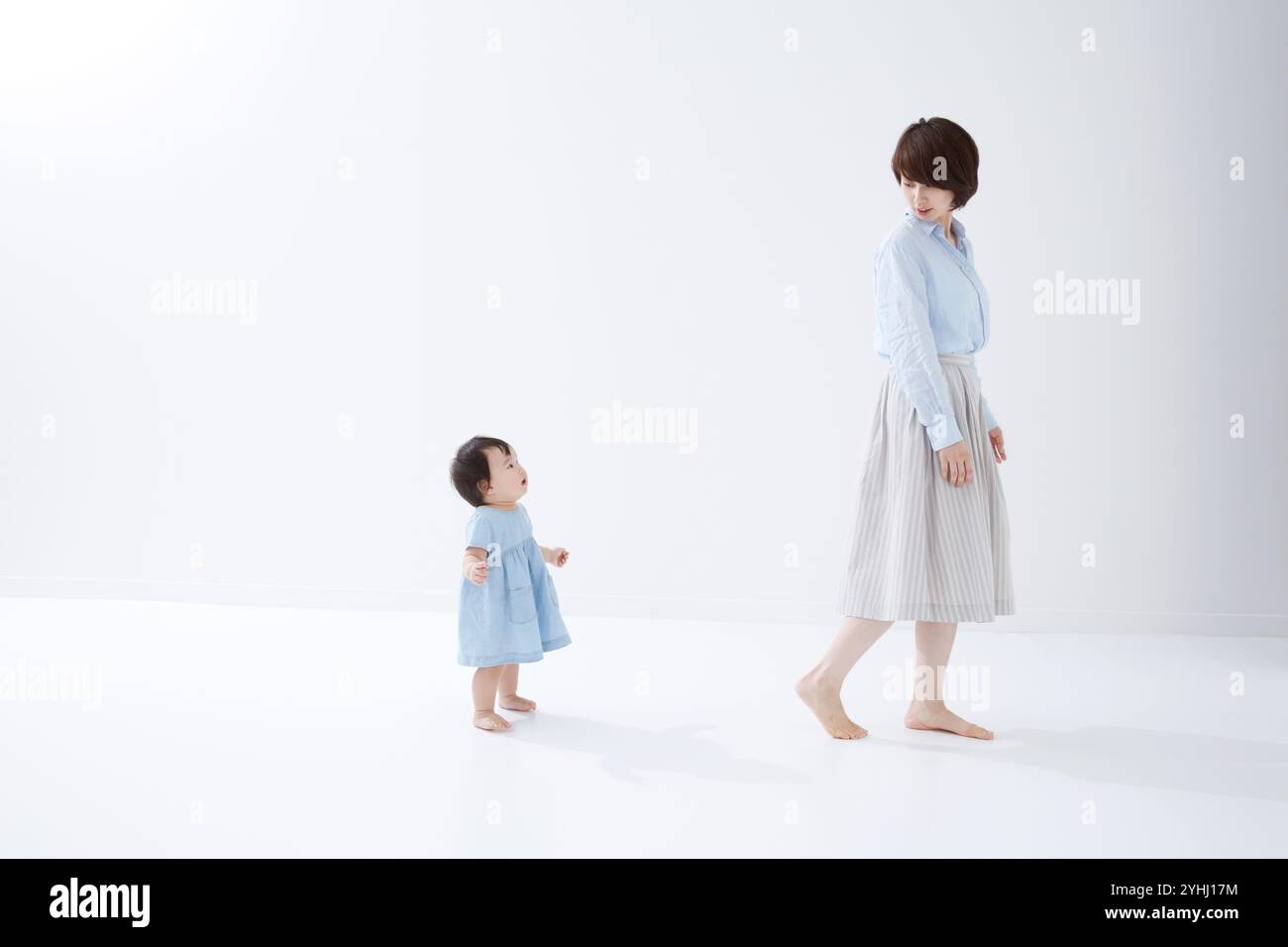 Mother looking back at standing baby Stock Photo - Alamy