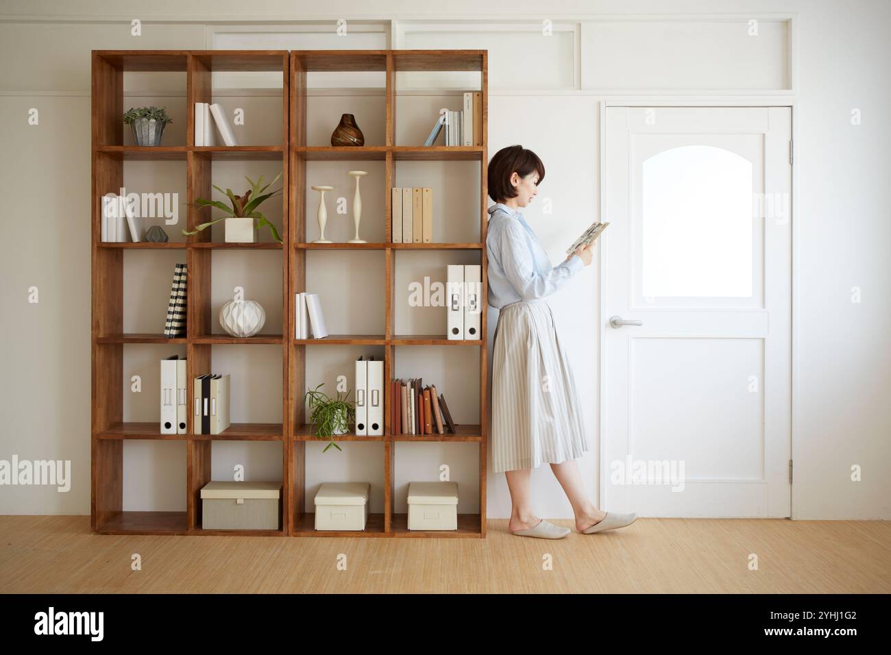 Woman reading a book next to a shelf Stock Photo - Alamy