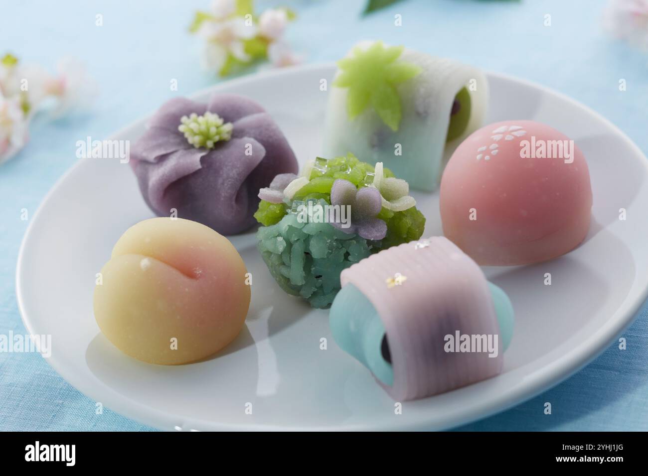 Pastel-coloured Japanese sweets and cherry blossoms on a round plate ...