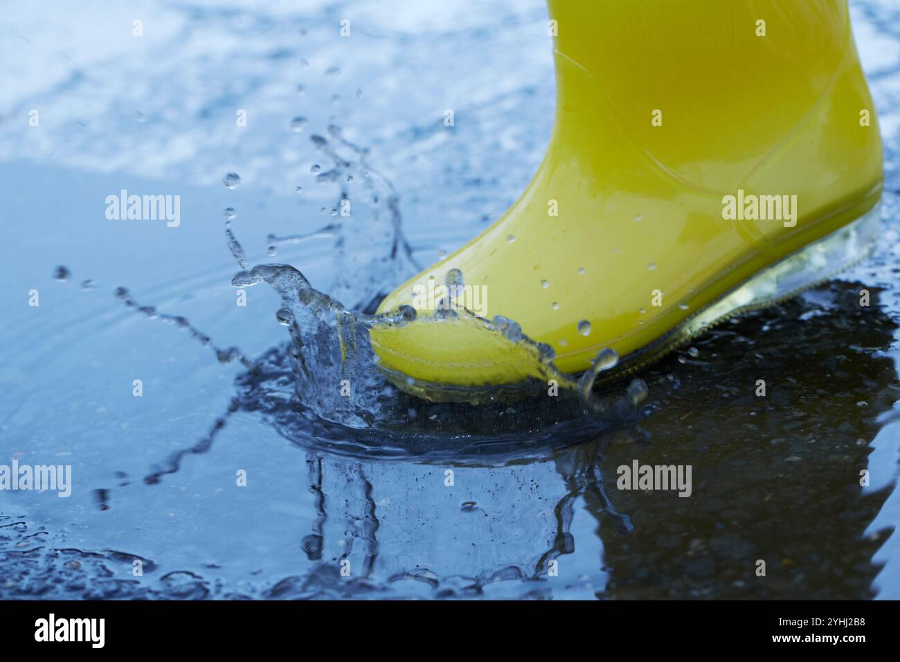 Woman splashing water in puddle with boots Stock Photo - Alamy