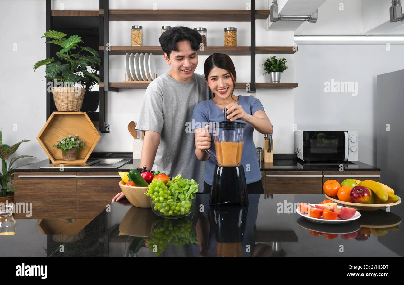 Young asian woman using blending machine mixing fruit and vegetable in ...