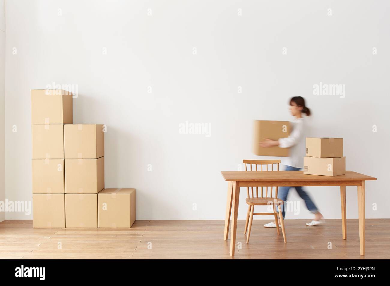 Pile of cardboard boxes and table and woman carrying boxes Stock Photo ...