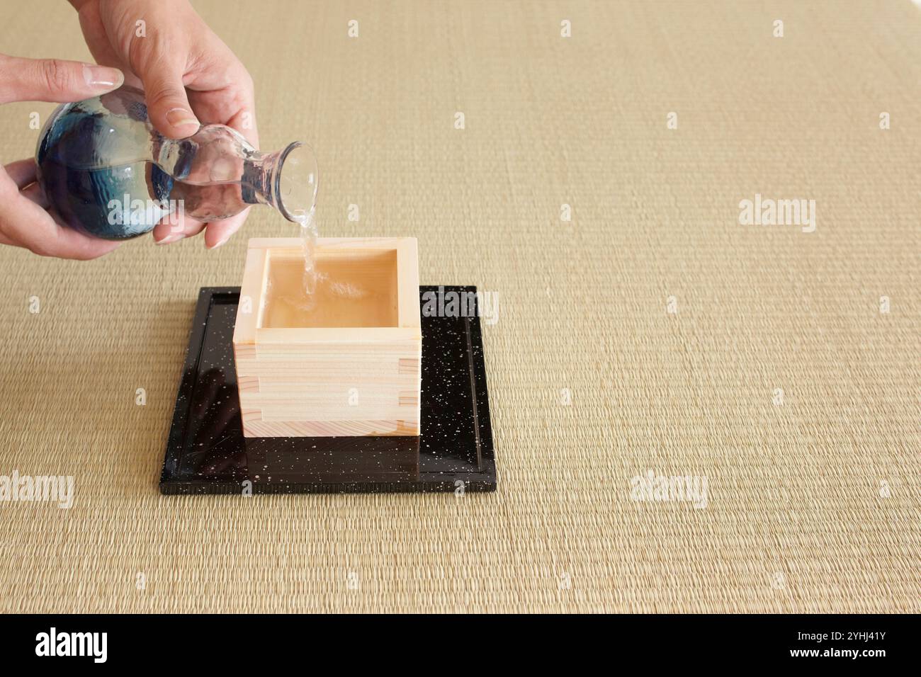 Woman's hand pouring sake Stock Photo - Alamy