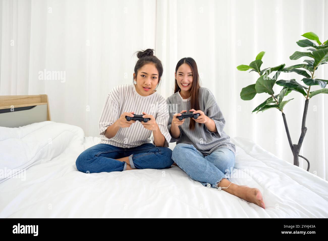Two Asian teenage girls playing console games in bed Stock Photo - Alamy