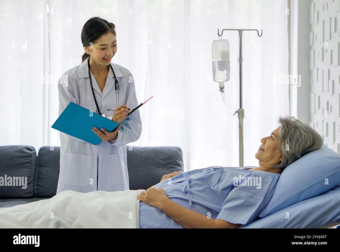 Young asian doctor in white gown with stethoscope and document folder ...