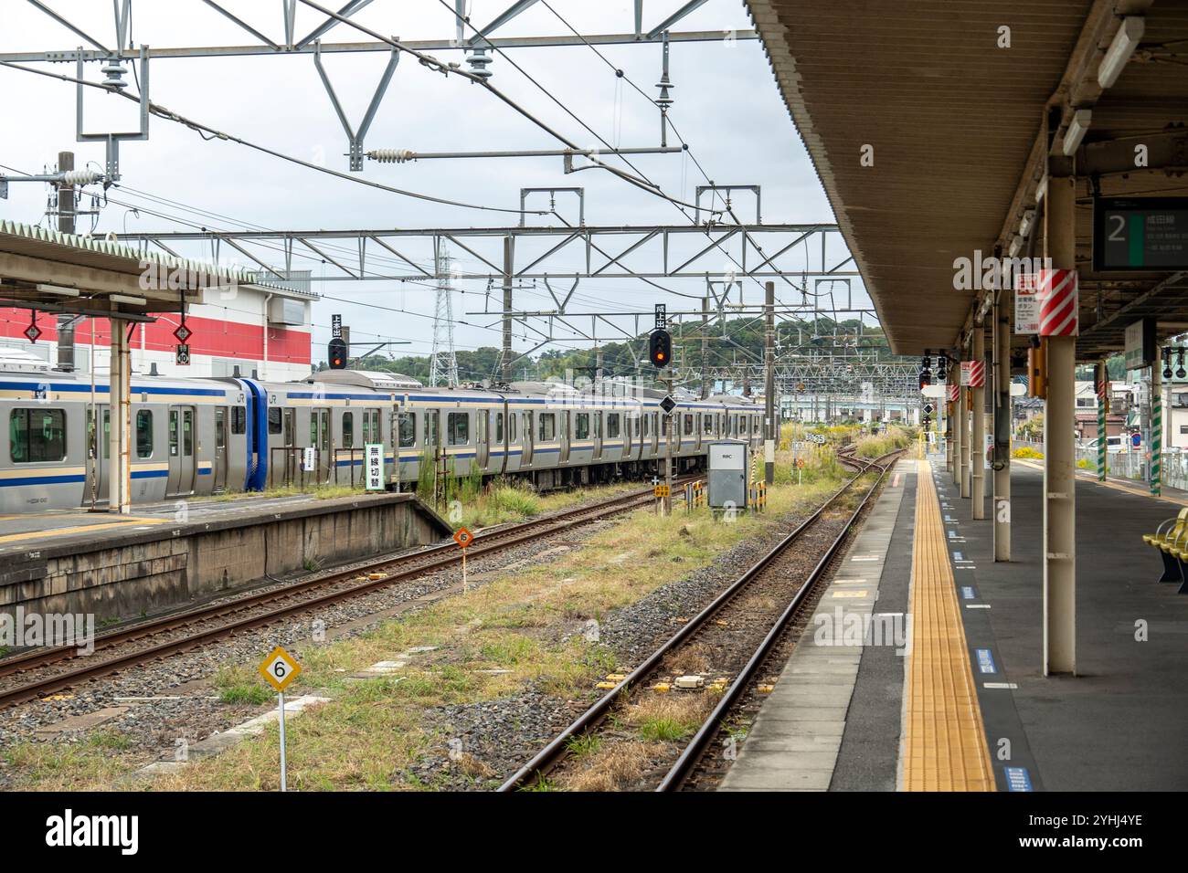 Trains stop at a quiet Japanese railway station on a cloudy day with ...