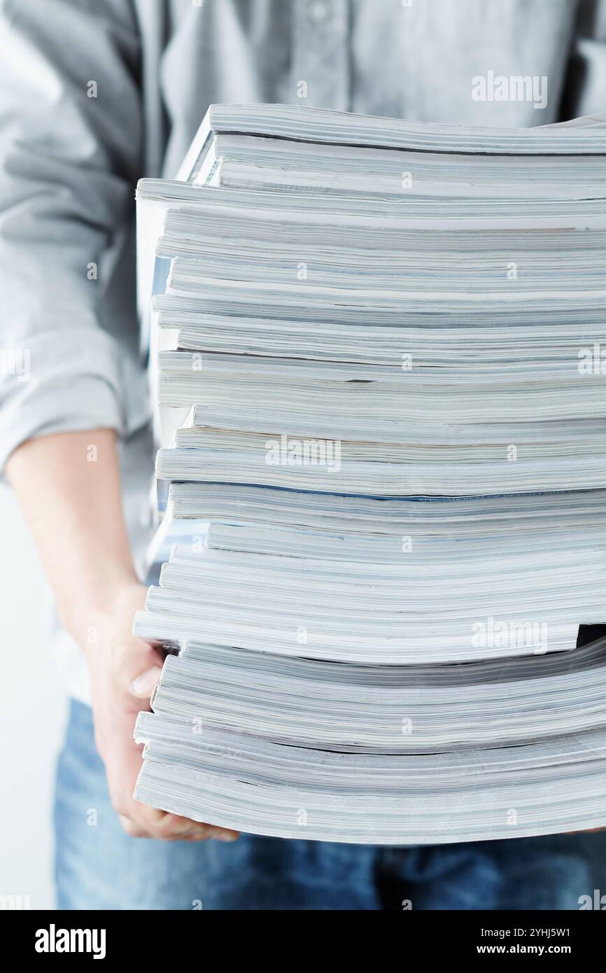 Person holding stack of magazines Stock Photo - Alamy
