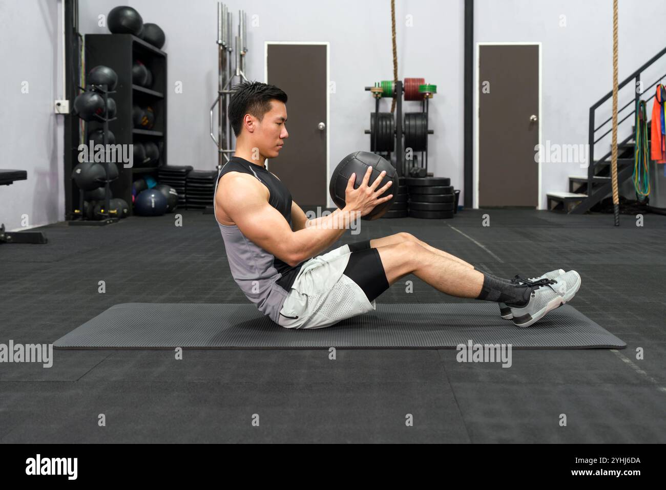A man exercises with a medicine ball in a gym, focusing on core ...
