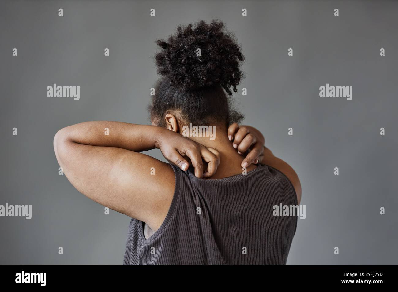 Unrecognizable Black woman scratching back and neck in minimal grey ...