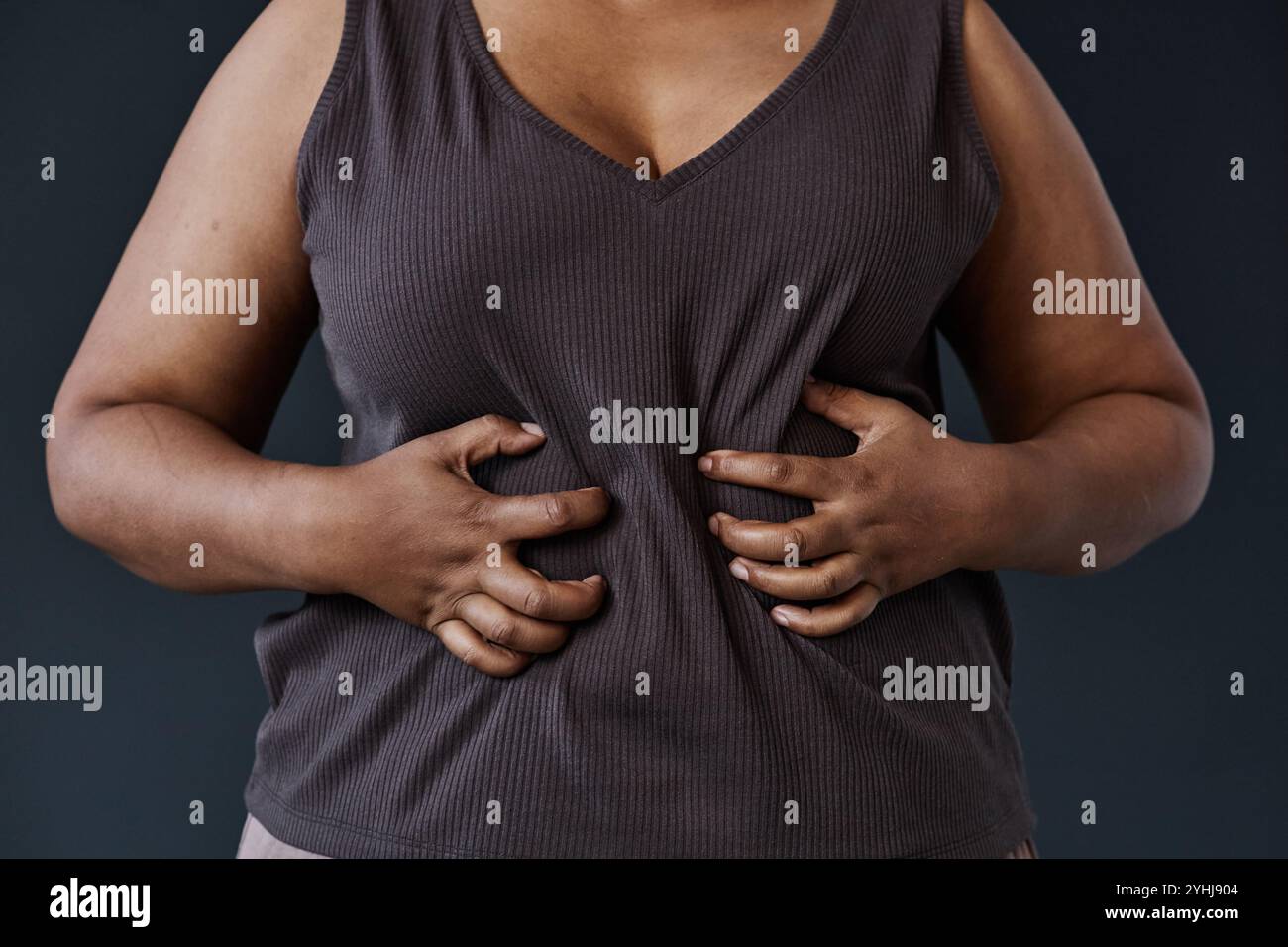 Close up of overweight Black woman scratching on tummy skin in minimal ...