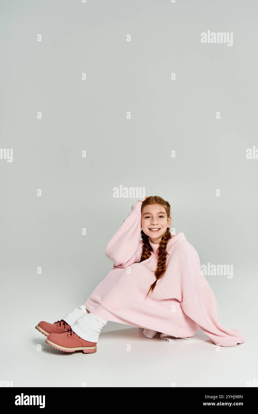 A happy girl sits comfortably, wearing warm winter clothing and smiling ...