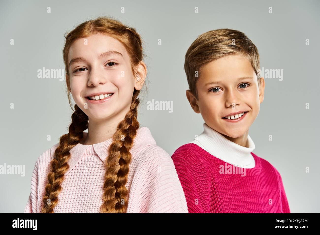 Two happy children wear cozy winter clothing while sharing a joyful ...