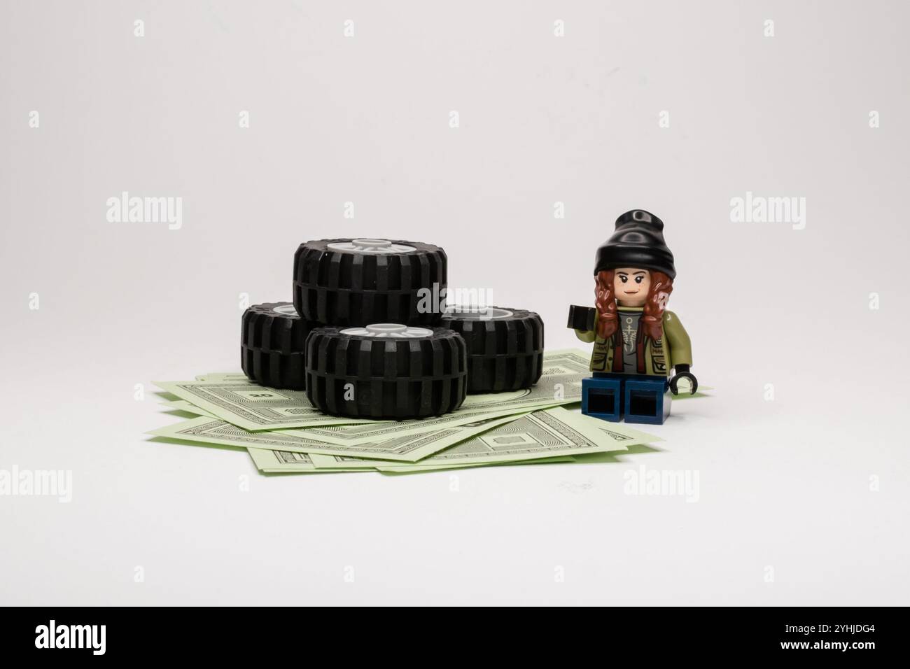 Lego girl sitting next to a pile of tires and money underneath them ...
