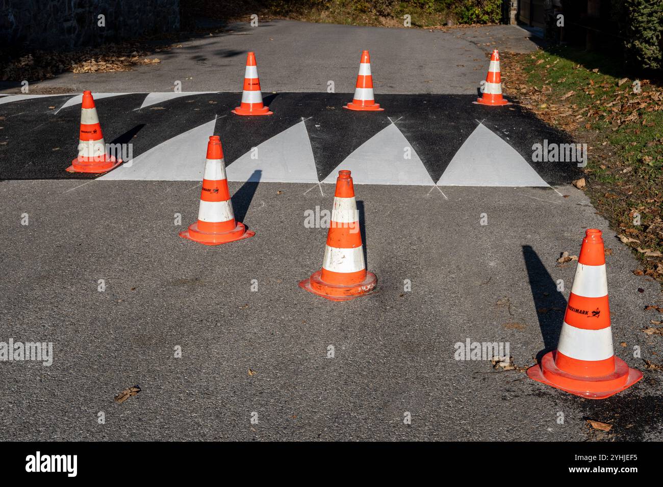 Multiple , orange traffic cones next to freshly painted road markers ...