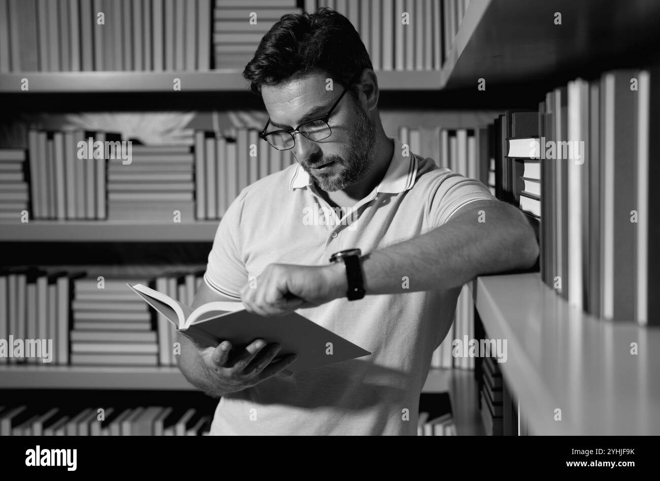 Middle aged teacher or professor in school library reading book ...
