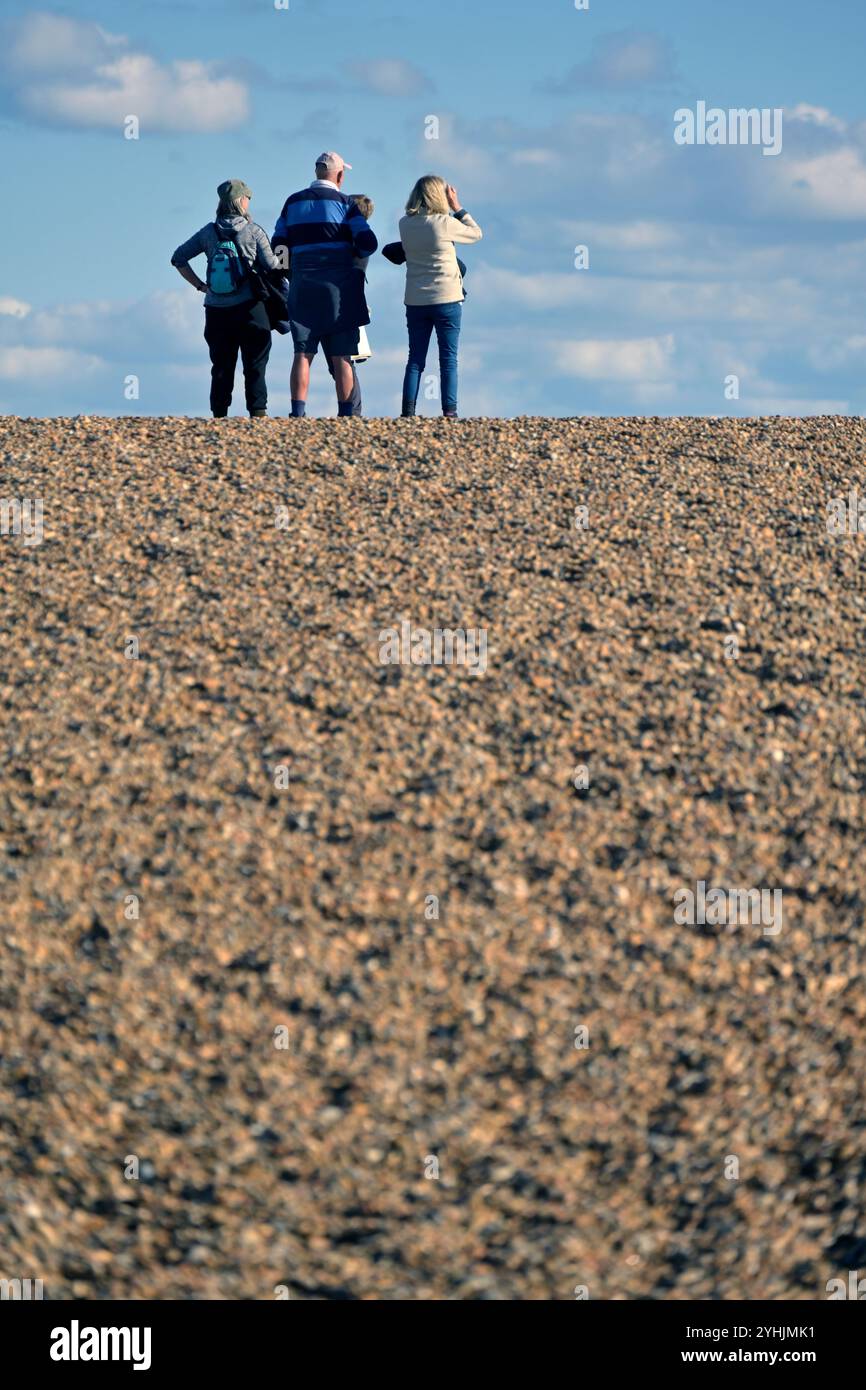 family group standing on shongle beach, shingle street, suffolk ...