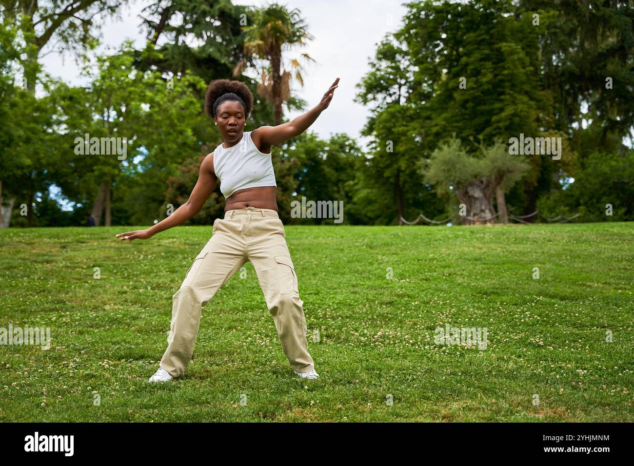 An African woman performs hip hop dance moves outdoors, showcasing her ...