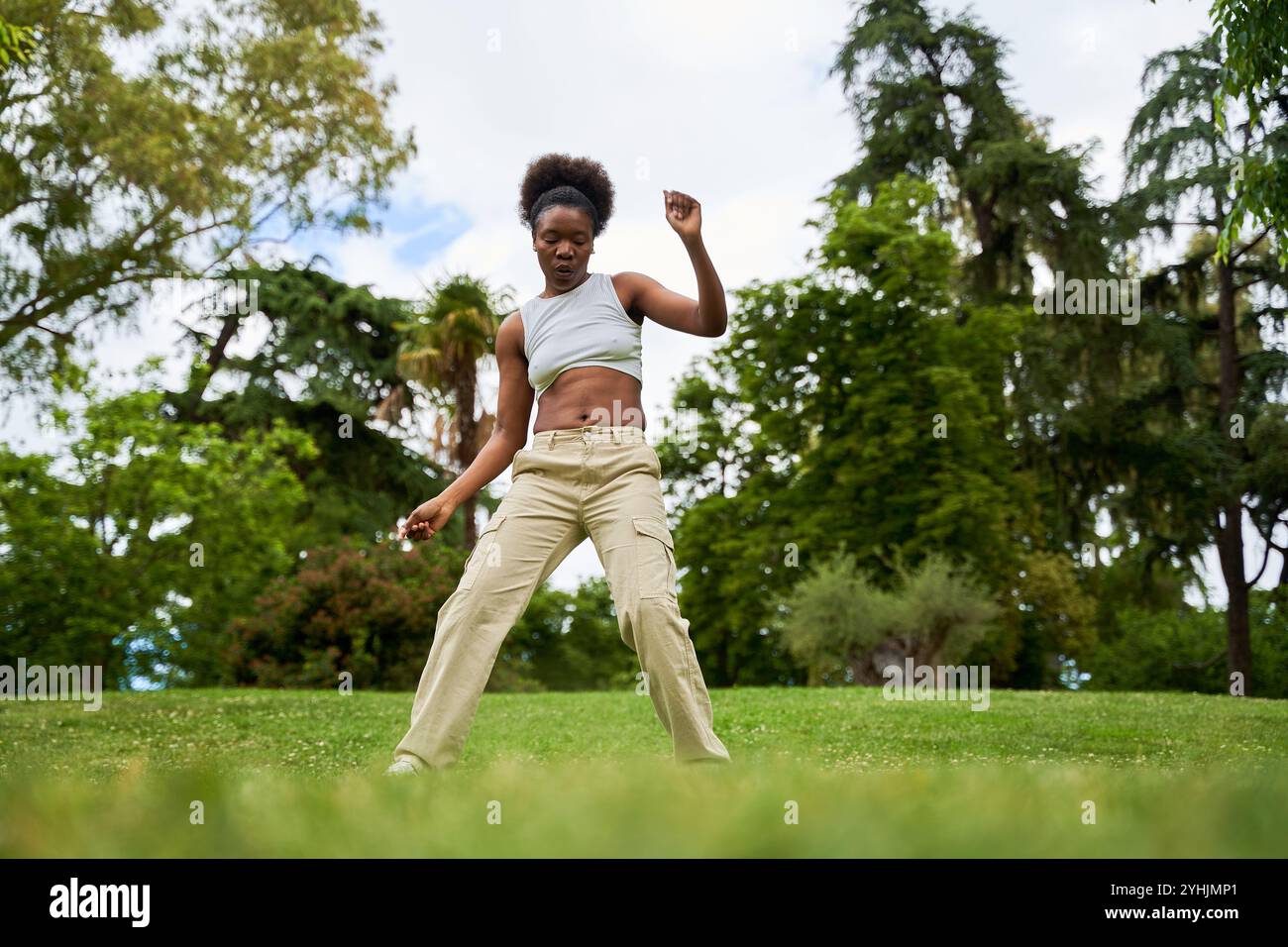 An African woman performs hip hop dance moves outdoors, showcasing her ...