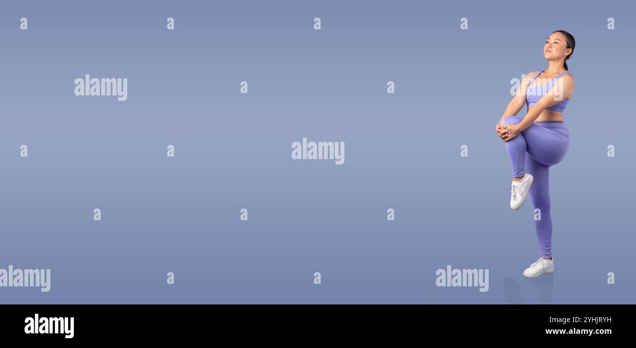 A woman performing a standing knee lift exercise in a studio setting ...