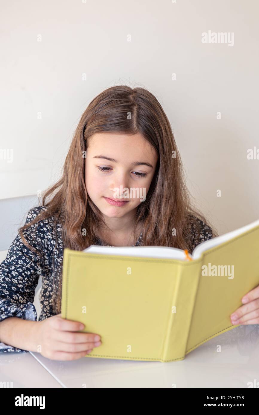 Sad girl reading a book at home. Girl student teaches lessons to school ...